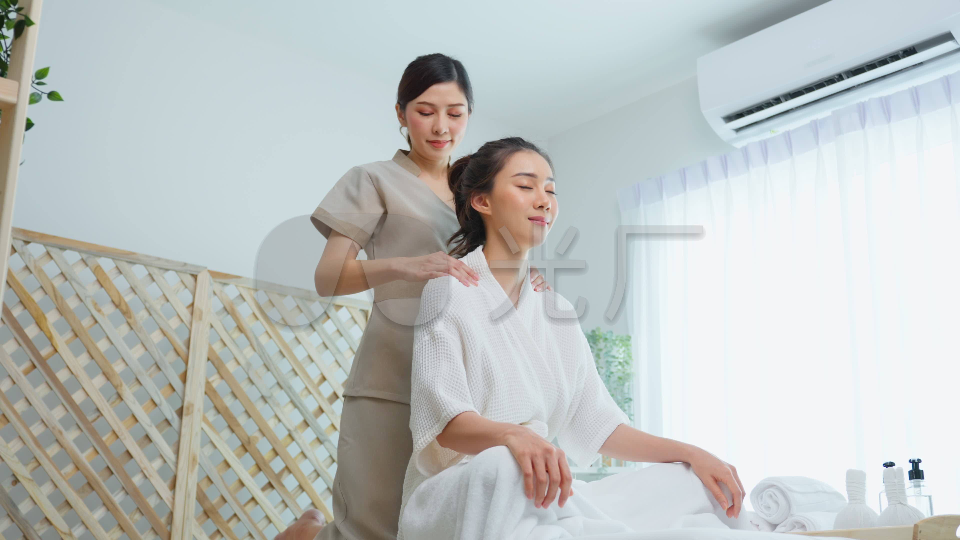 亚洲年轻快乐女性在肩部和背部按摩时感到放松。美丽迷人的女孩坐在按摩台上,在spa美容院接受按摩师的理3840x2160高清视频素材下载