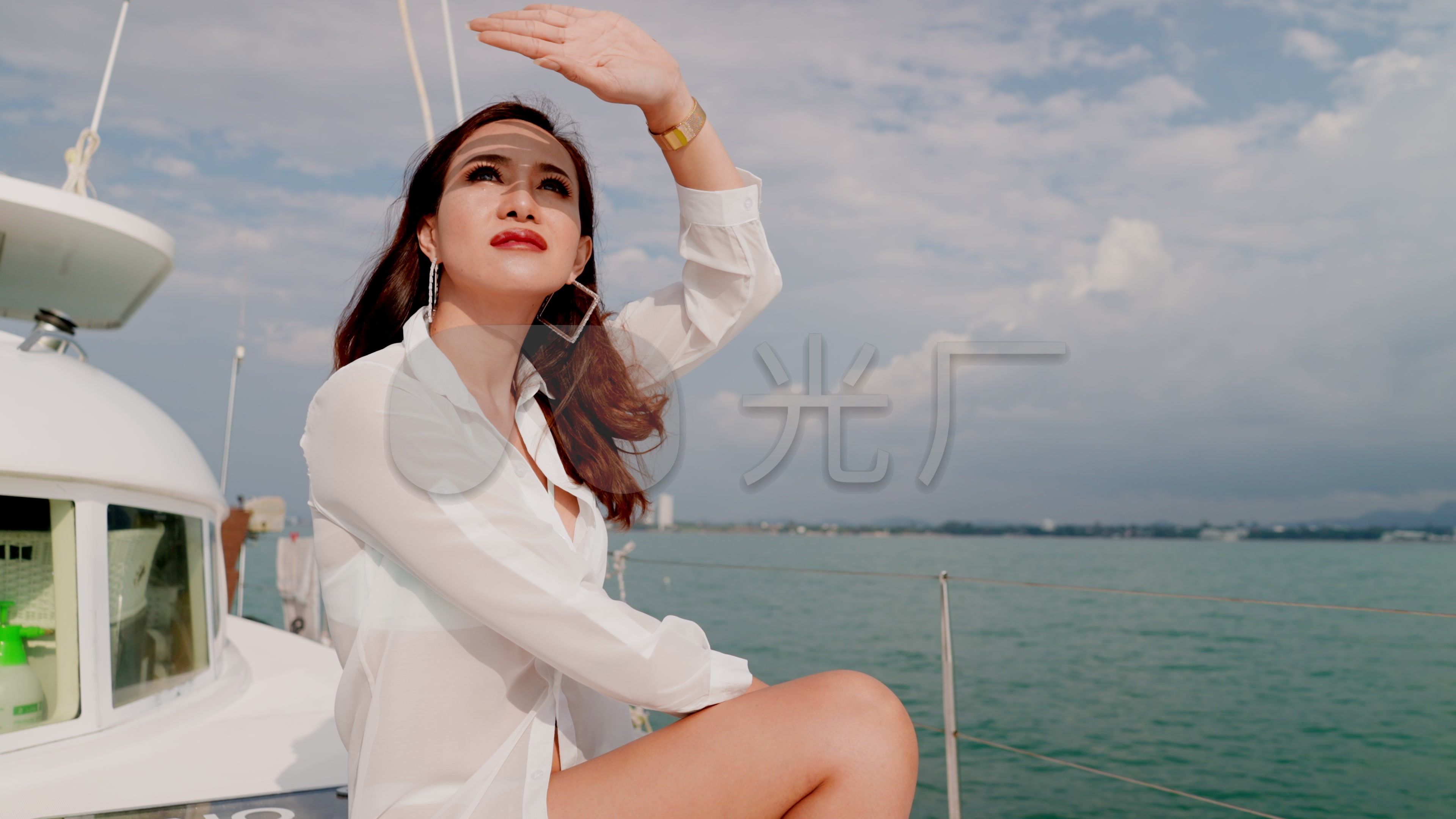 一位美女穿着白色束腰外衣在游船上放松,举手保护脸部免受阳光照射,享受美景。海上暑假。3840x2160高清视频素材下载编号