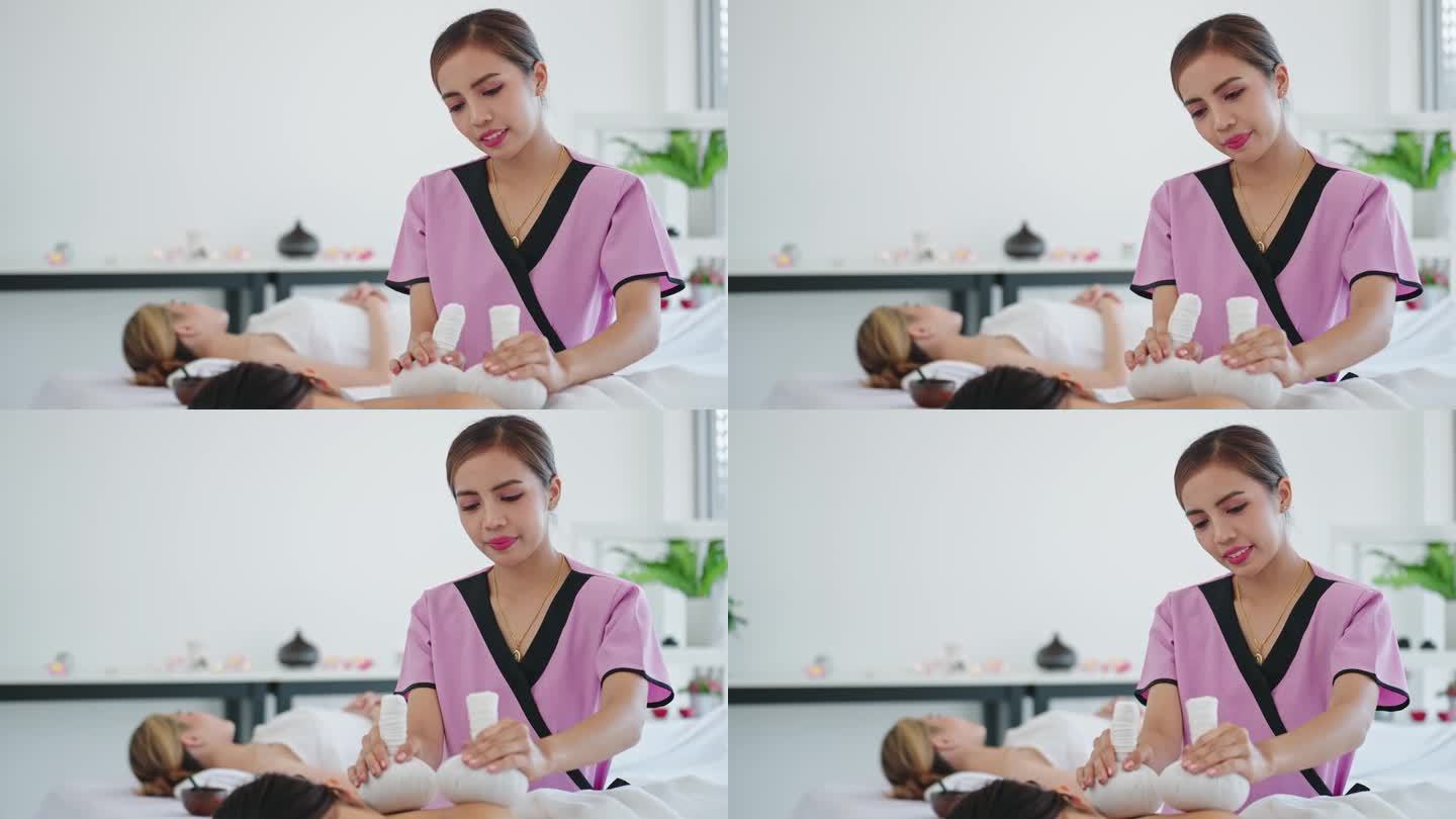专业女性按摩师使用草药按摩球按摩女性背部。治疗背部疼痛，肌肉疼痛。泰式按摩，spa身体按摩治疗视频素材下载编号24807622光厂vj师网